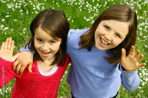 "Two cute girls waving hello with grass in background." Stock photo and ...