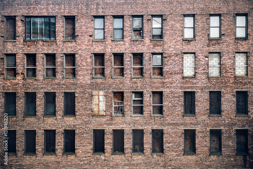 "Front view of a boarded-up abandoned brick skyscraper building windows ...