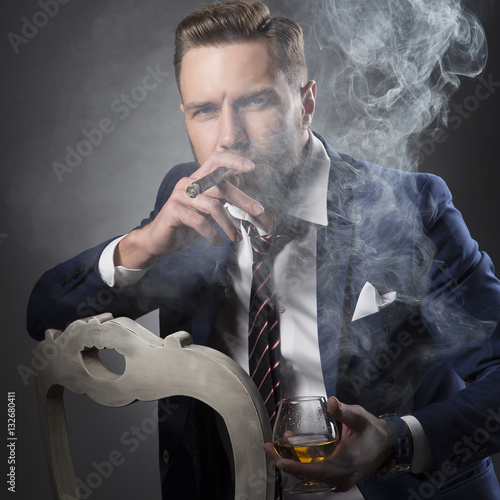 Handsome Young Man Smoking Cigar With Cognac Glass In Hand Wearing
