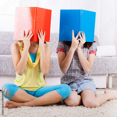 "Two girls with books, covering their faces." Stock photo and royalty ...