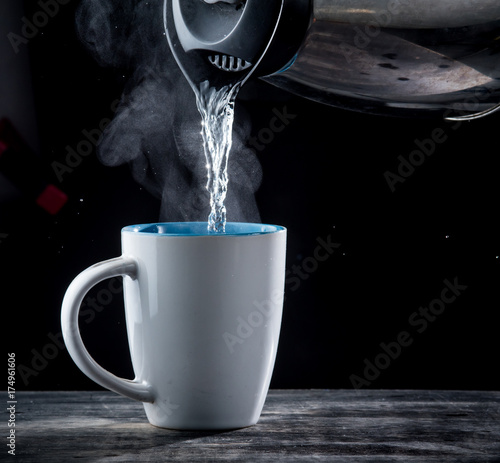 "Pouring hot water into into a cup on a black background" Stock photo ...