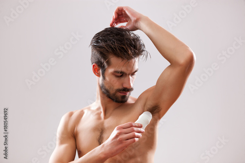 "Young man is applying roll on antiperspirant to his armpit. " Stock ...