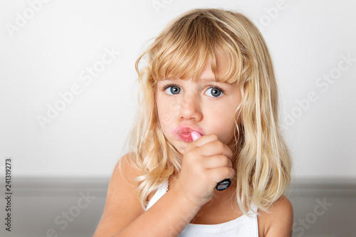 "Portrait of girl with blond hair applying lipstick" Stock photo and ...
