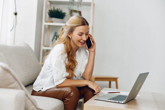 Woman Multitasking on Sofa with Laptop and Documents
